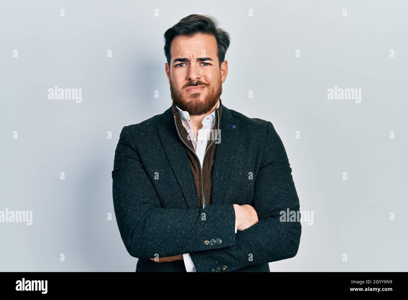 Handsome caucasian man with beard with arms crossed gesture clueless ...