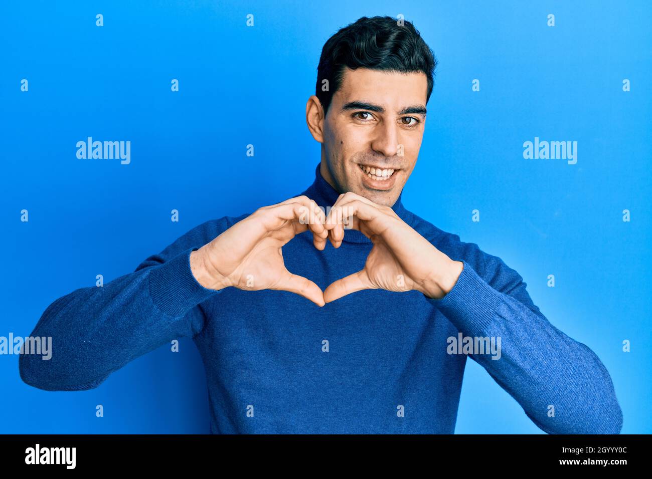 Handsome hispanic man wearing turtleneck sweater smiling in love doing ...