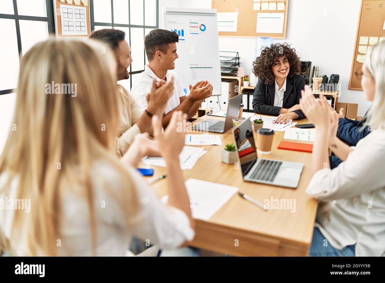 Group of young business workers smiling and clapping to partner at the ...
