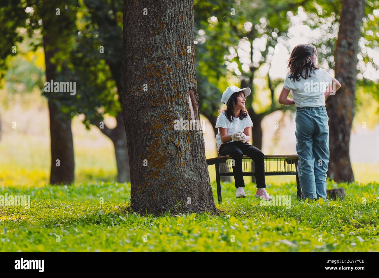 Close up photo of two girls outdoors, one girl posing standing with the ...