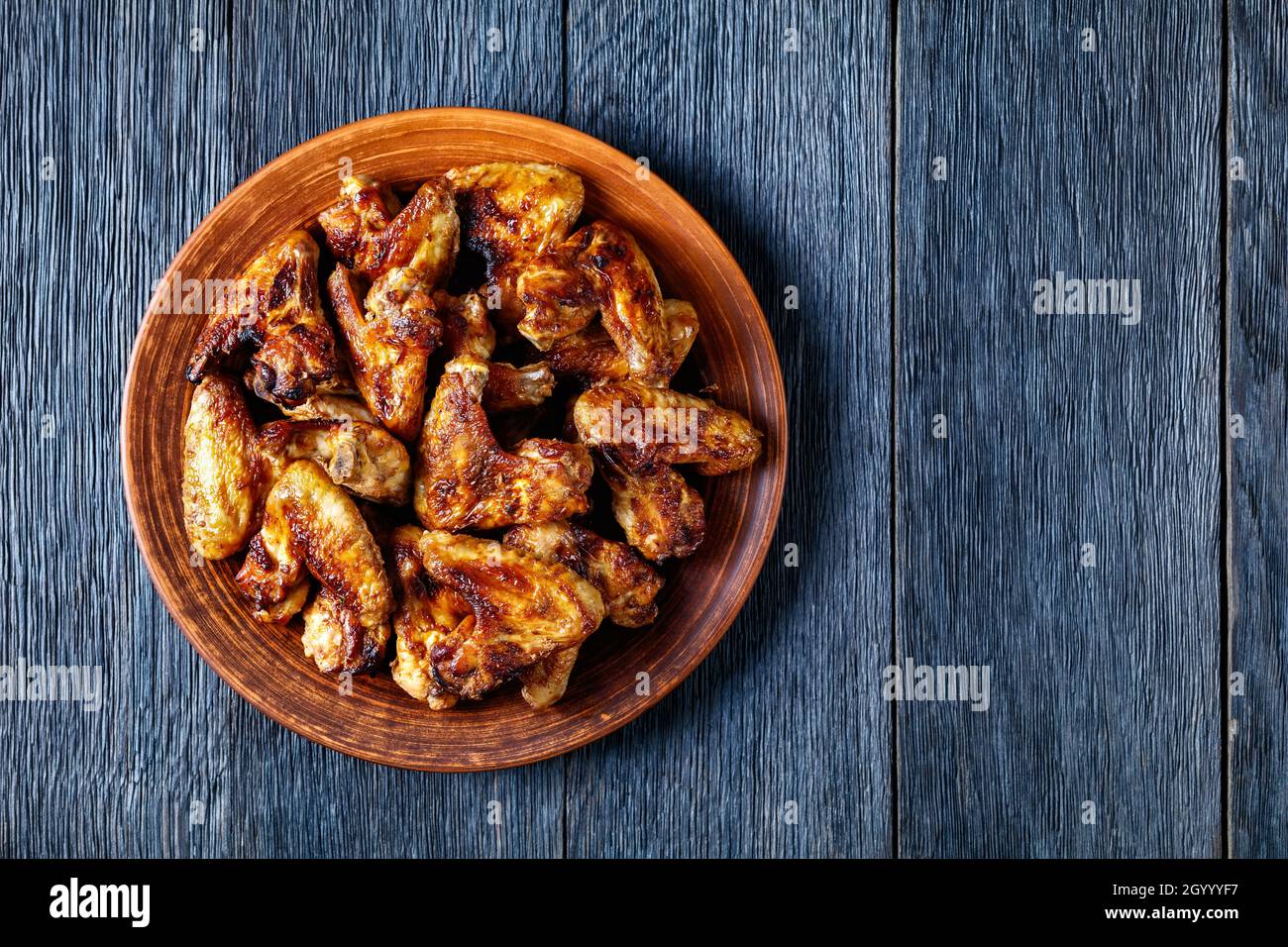 crispy fried chicken wings served on a clay plate on a wooden table ...