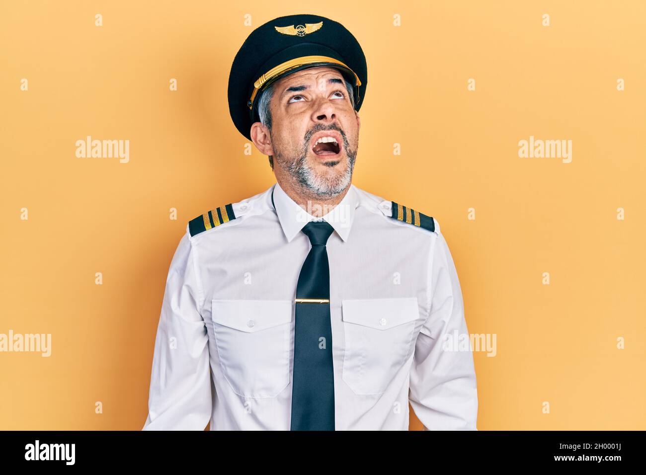 Handsome middle age man with grey hair wearing airplane pilot uniform ...