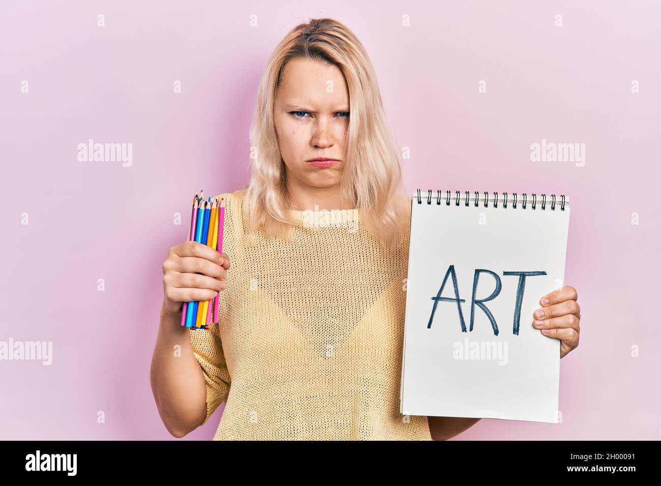 Beautiful caucasian blonde woman holding art notebook and color pencils ...