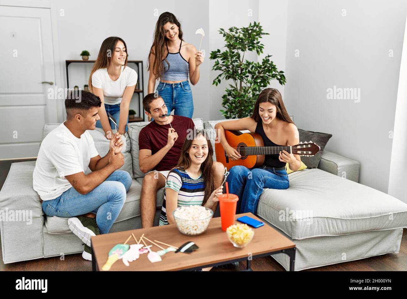 Group of young friends having party playing classical guitar at home ...