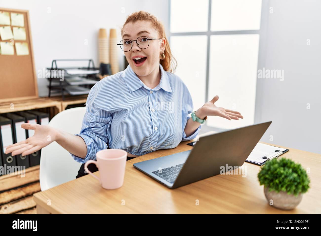 Young redhead woman working at the office using computer laptop smiling ...