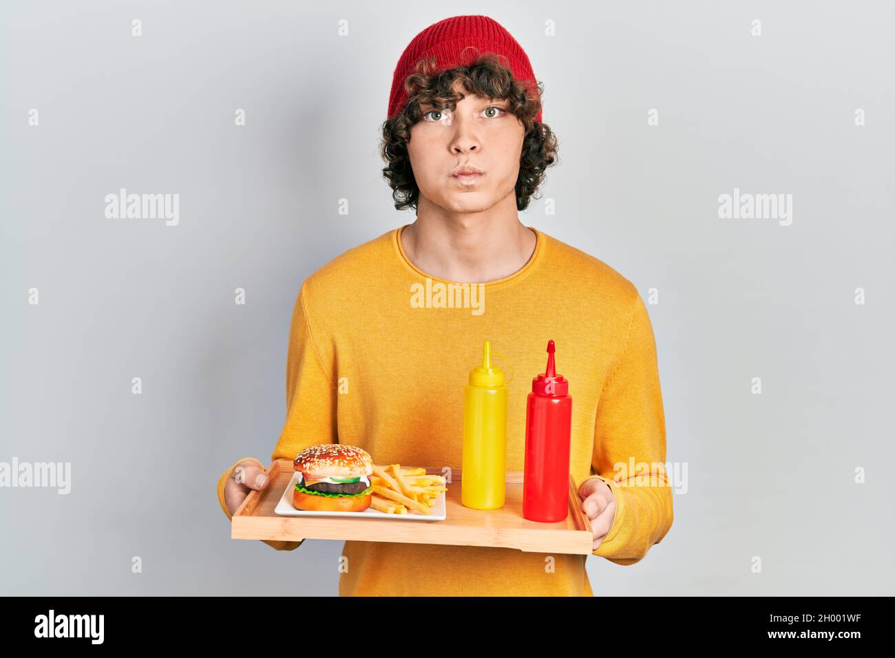 Handsome young man eating a tasty classic burger with ketchup and ...