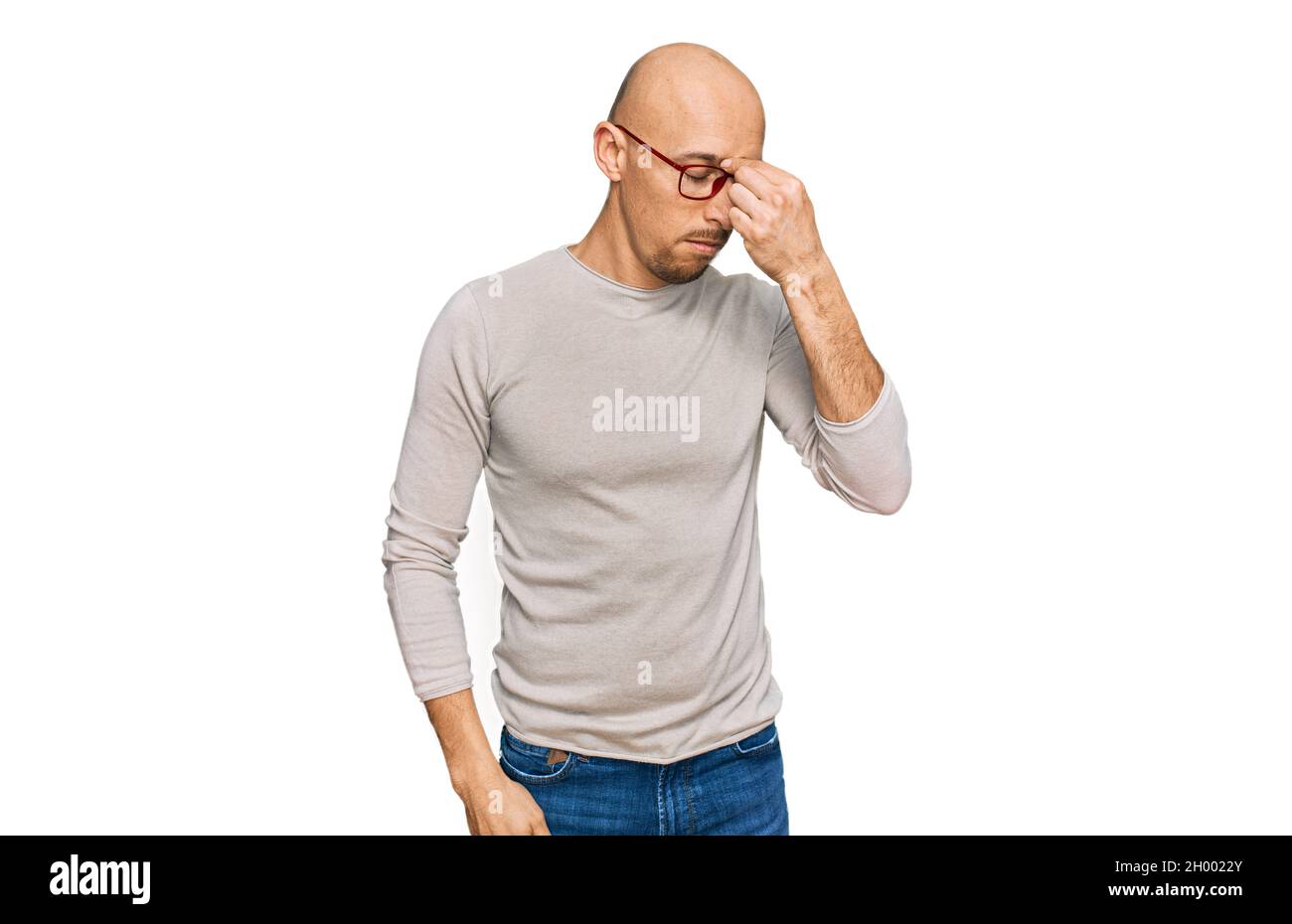 Bald man with beard wearing casual clothes and glasses tired rubbing ...