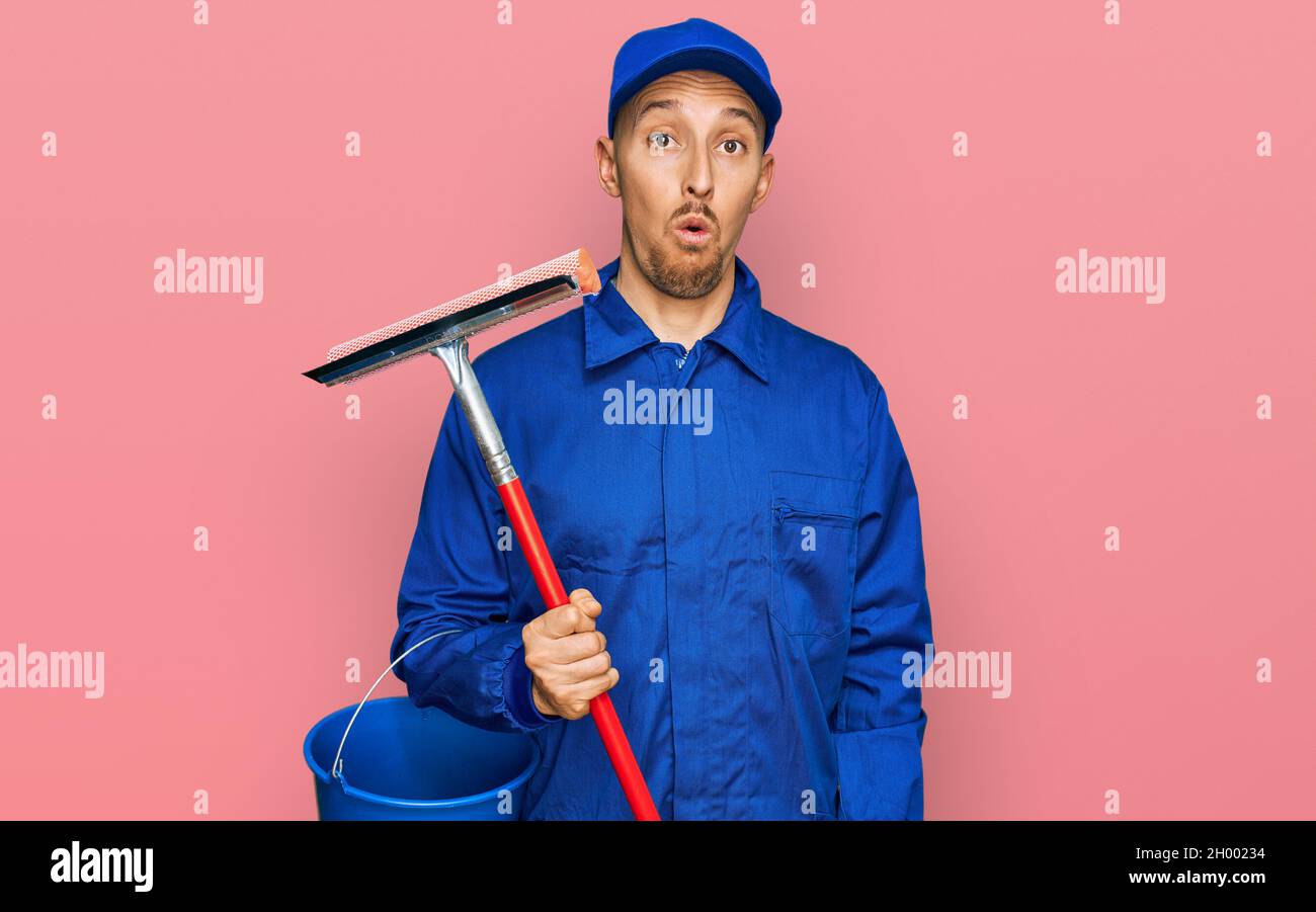 Bald man with beard wearing glass cleaner uniform and squeegee scared ...