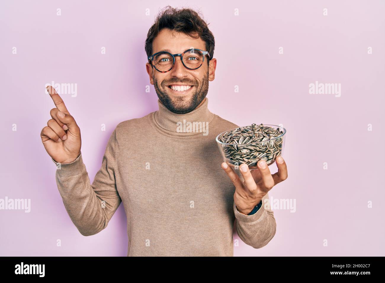 Handsome man with beard football reporter holding pumpkin seeds bowl ...