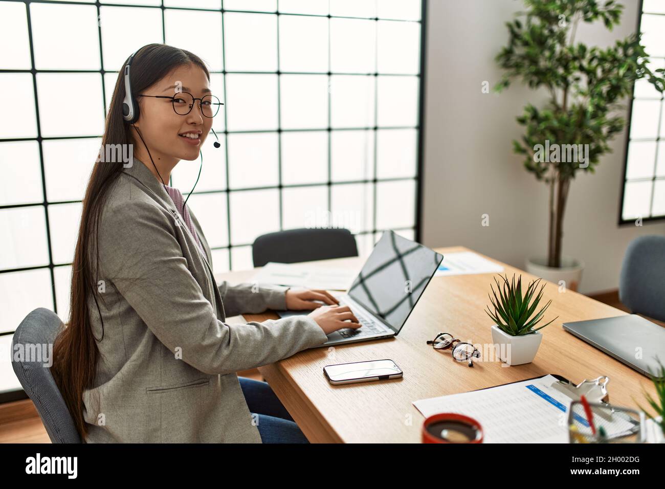 Young chinese call center agent woman smiling happy working at the ...