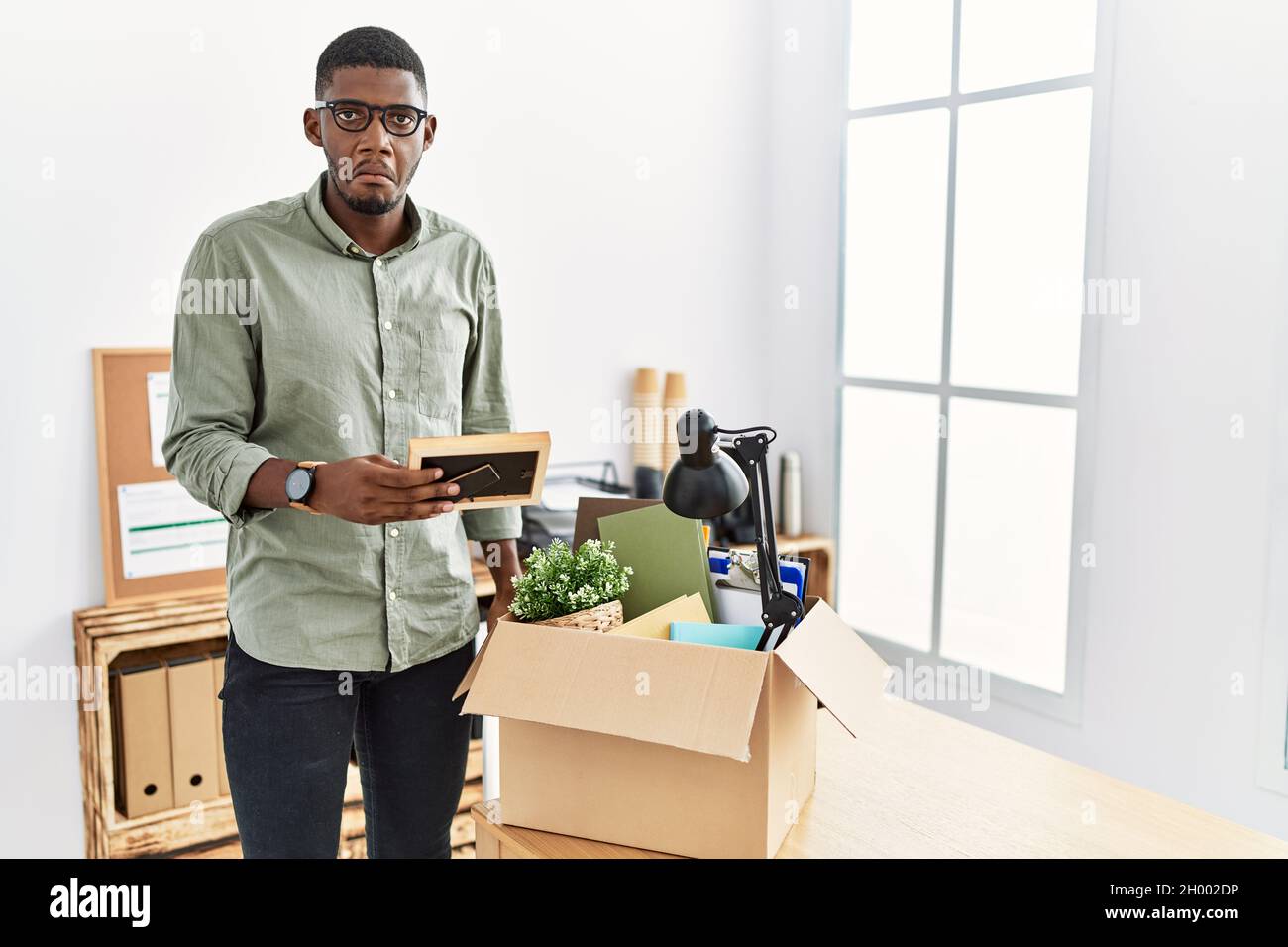 Young african american businessman unboxing box at the office depressed ...