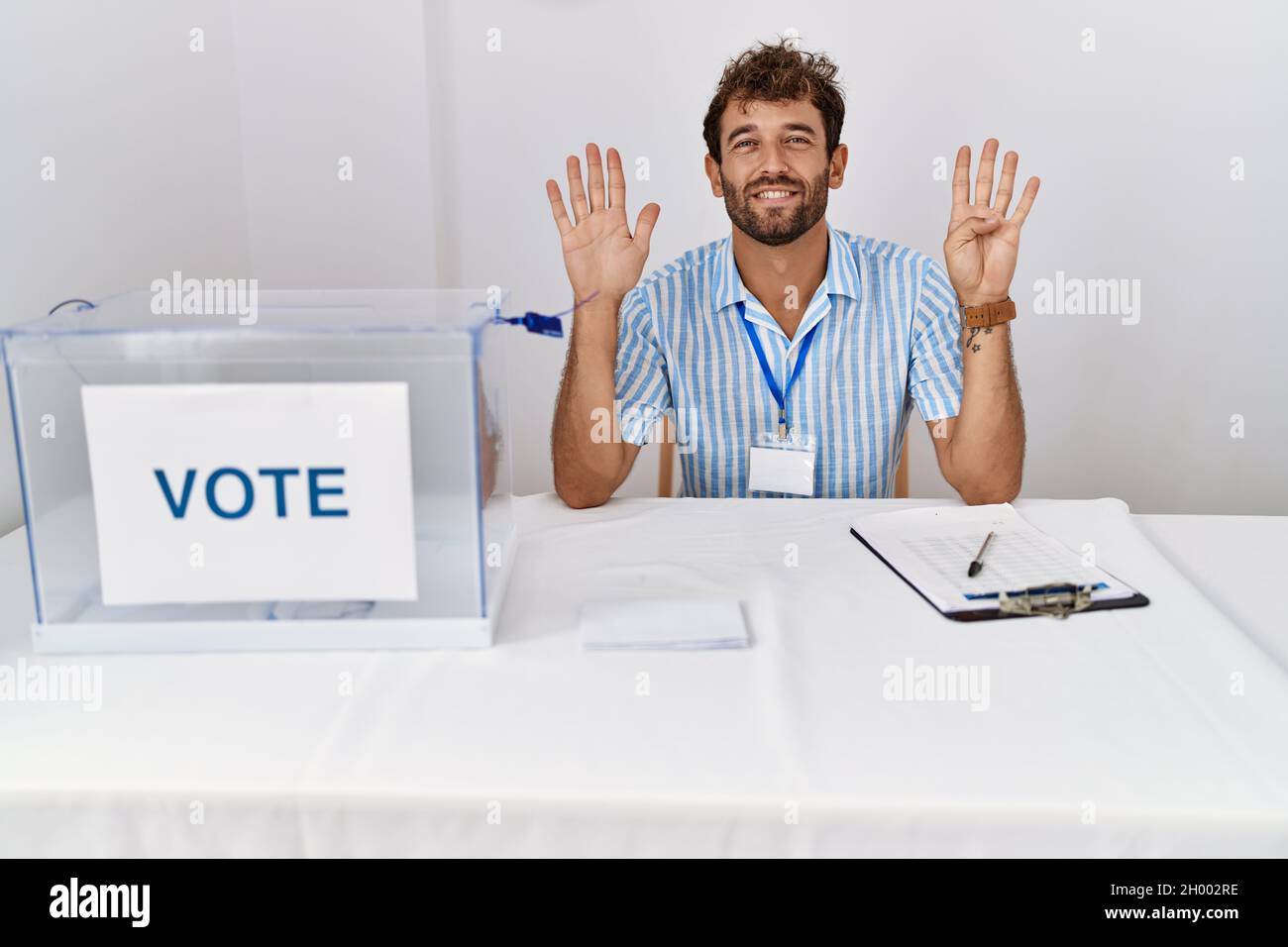 Young handsome man at political election sitting by ballot showing and ...