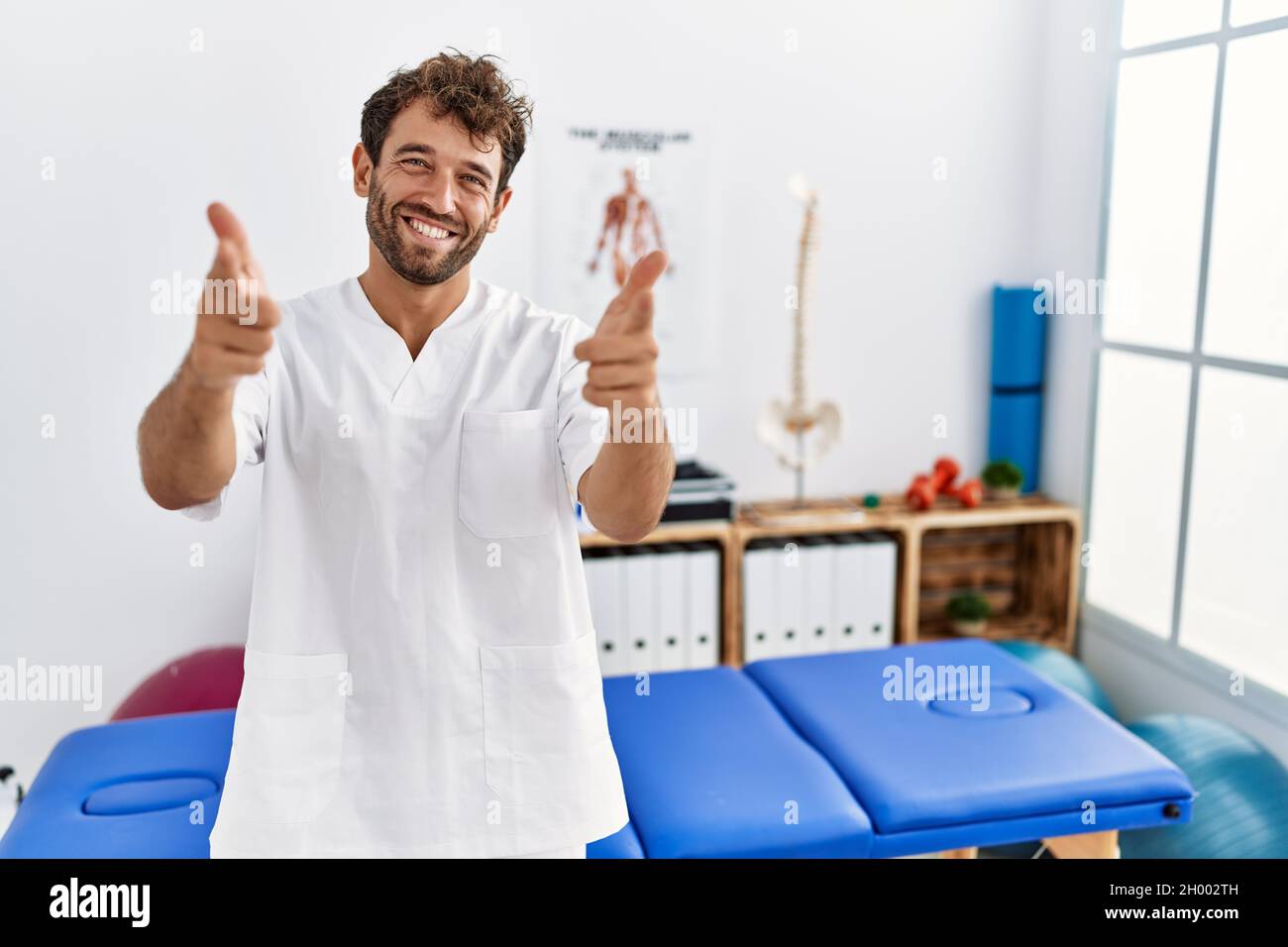 Young handsome physiotherapist man working at pain recovery clinic ...