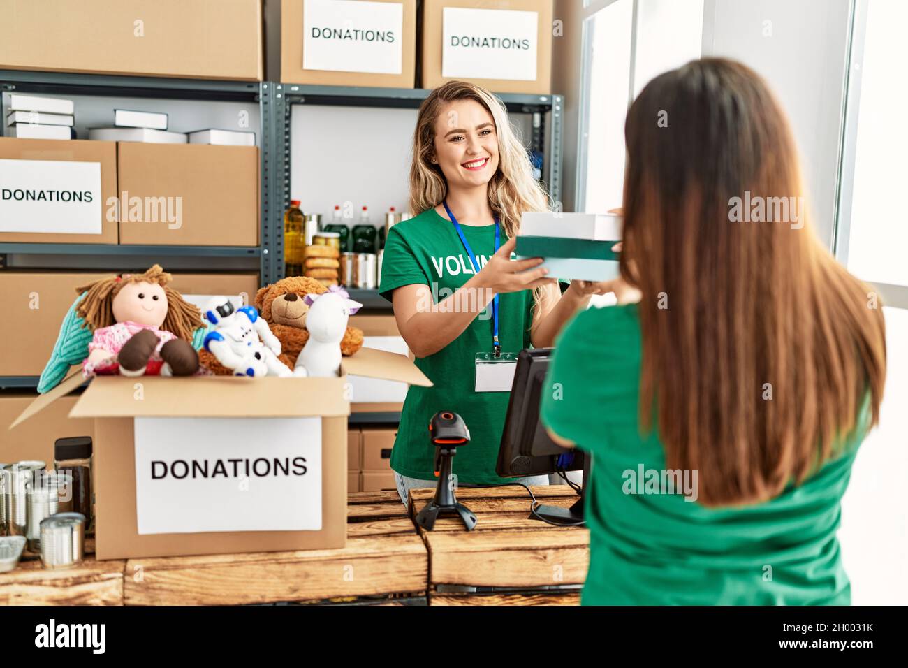 Young volunteer girl helping woman at charity center Stock Photo - Alamy