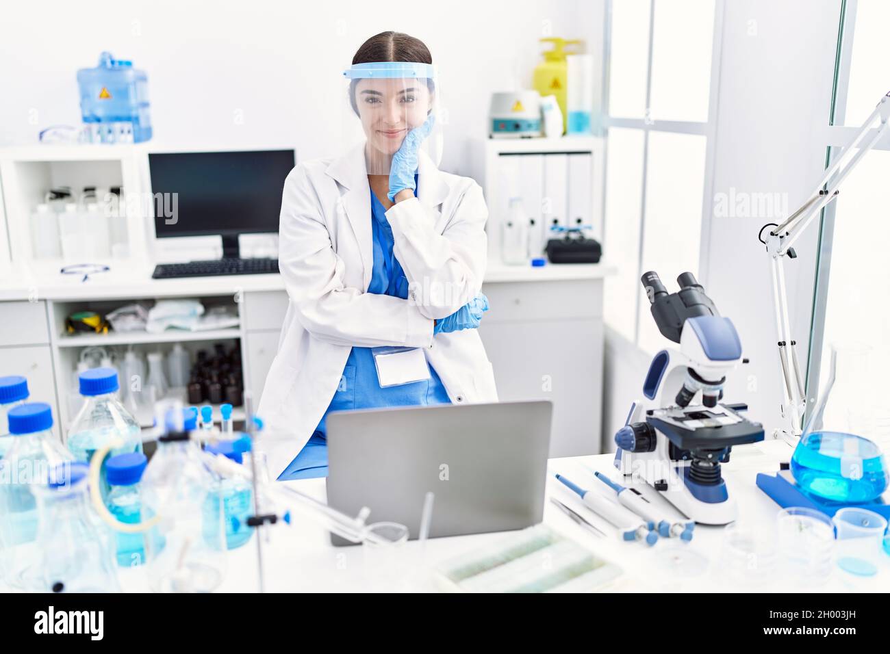 Young hispanic woman wearing scientist uniform thinking looking tired ...