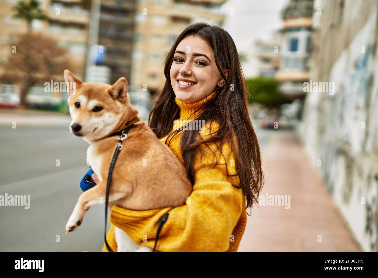 Beautiful young woman hugging happy shiba inu dog at street Stock Photo ...