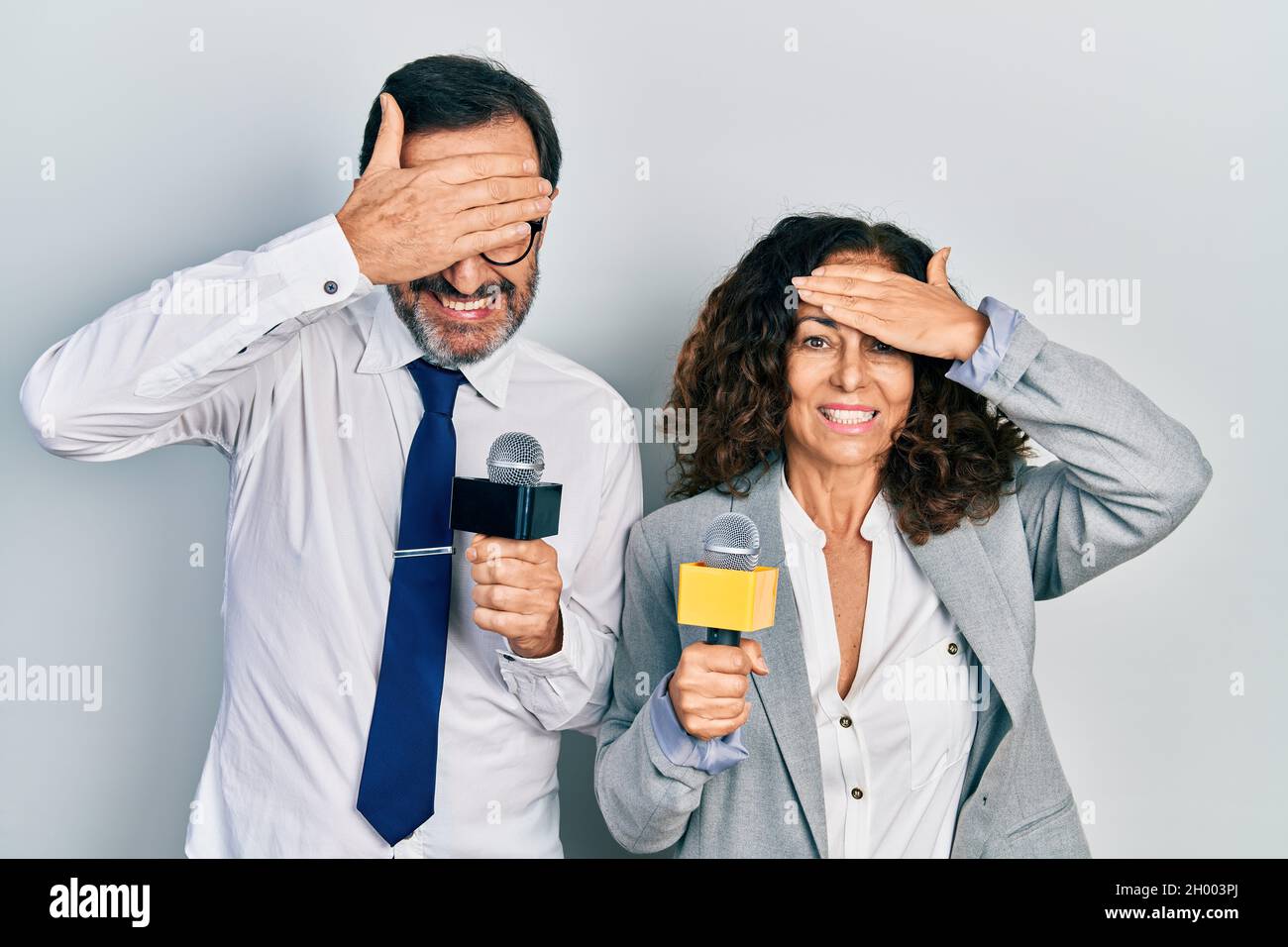 Middle age couple of hispanic woman and man holding reporter ...
