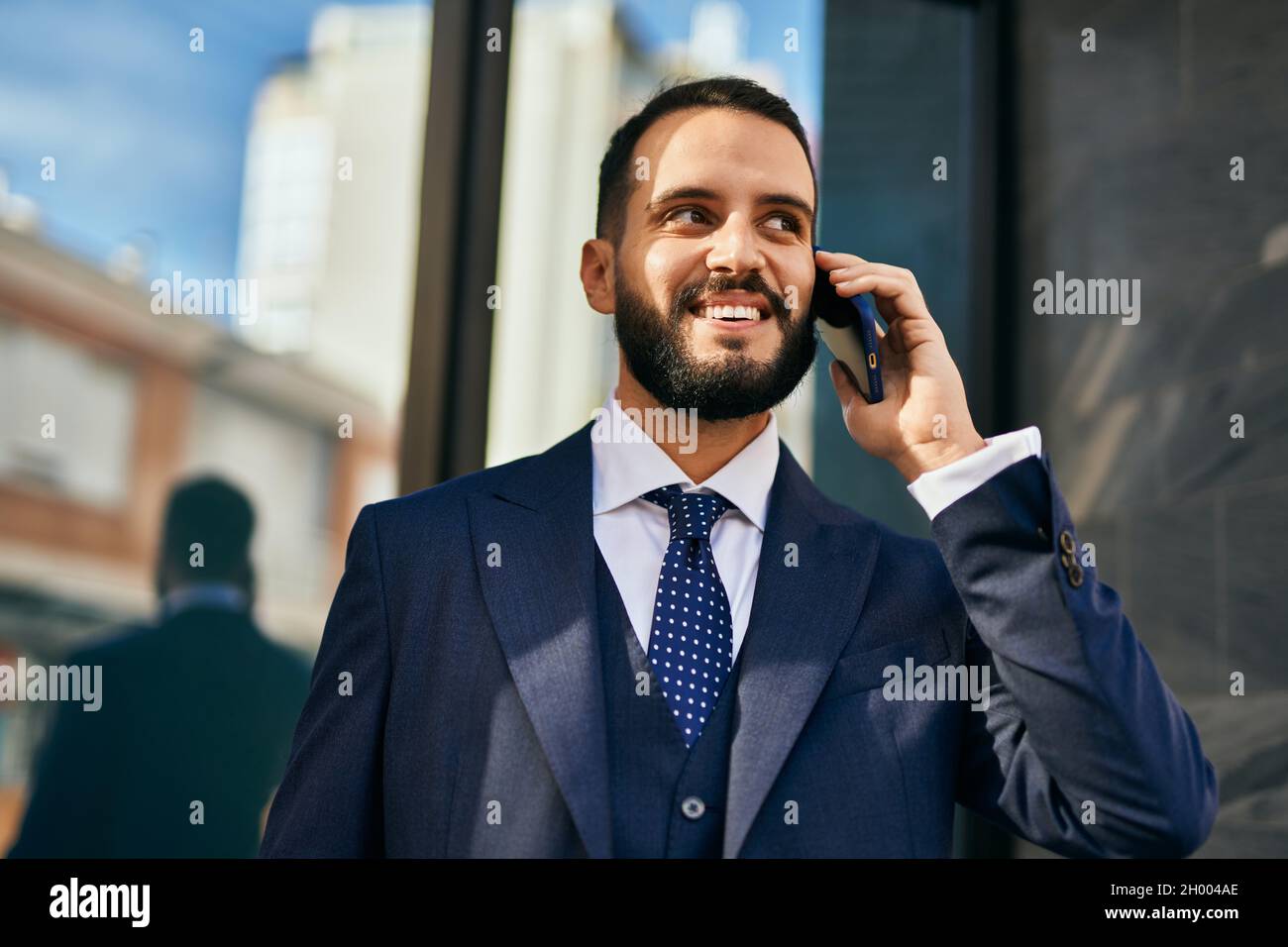 Young businessman smiling happy talking on the smartphone at the city ...