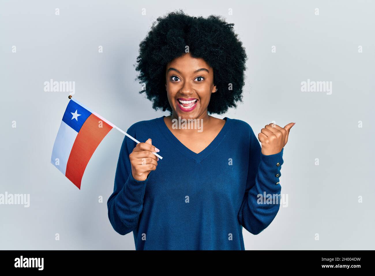 Young african american woman holding chile flag pointing thumb up to ...