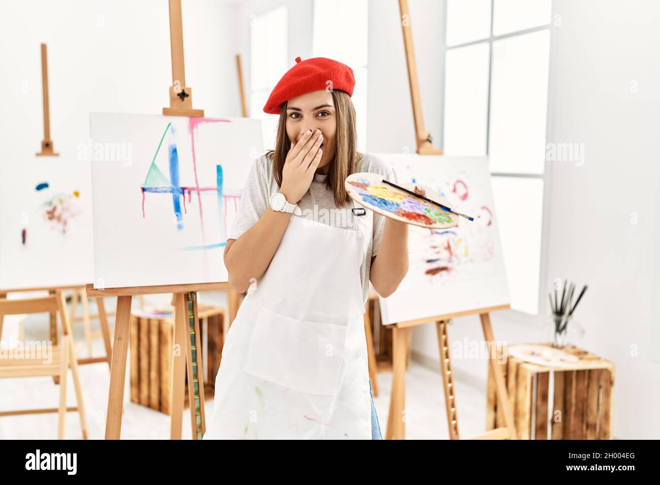 Young artist woman painting on a canvas at art studio laughing and ...