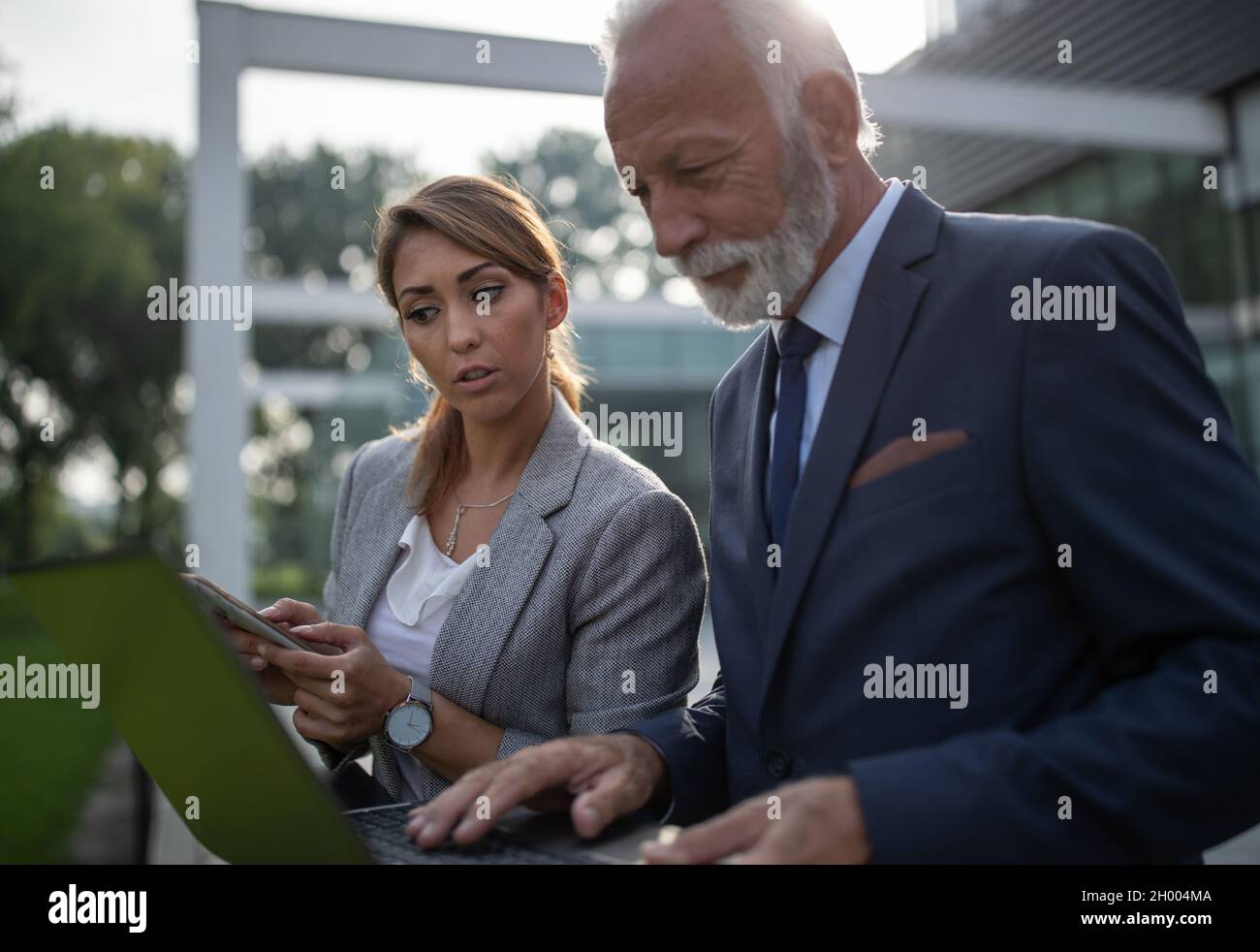 Mature businessman and young woman looking at tablet and solving ...