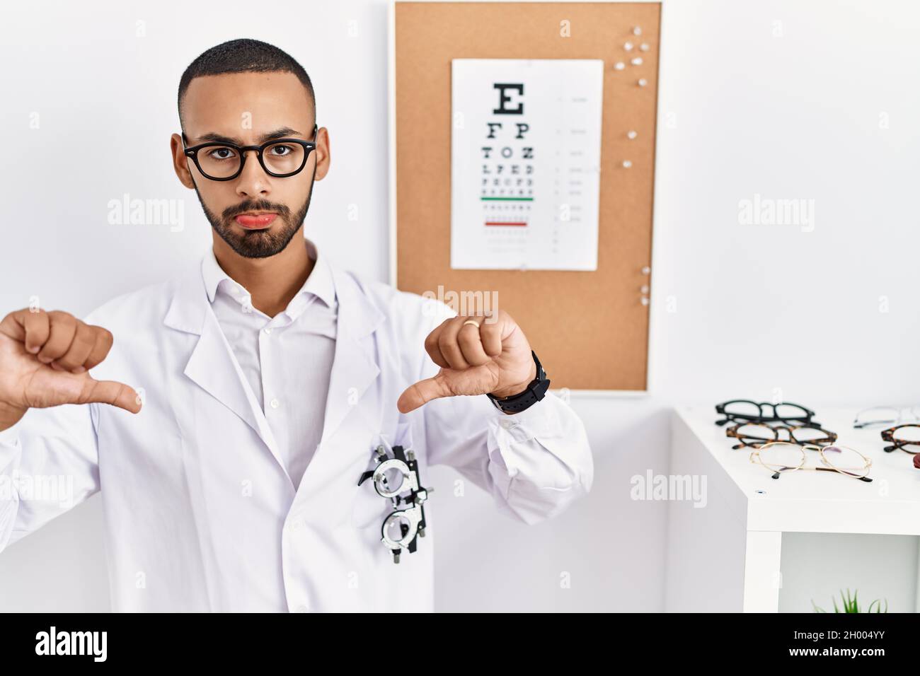 African american optician man standing by eyesight test pointing down ...