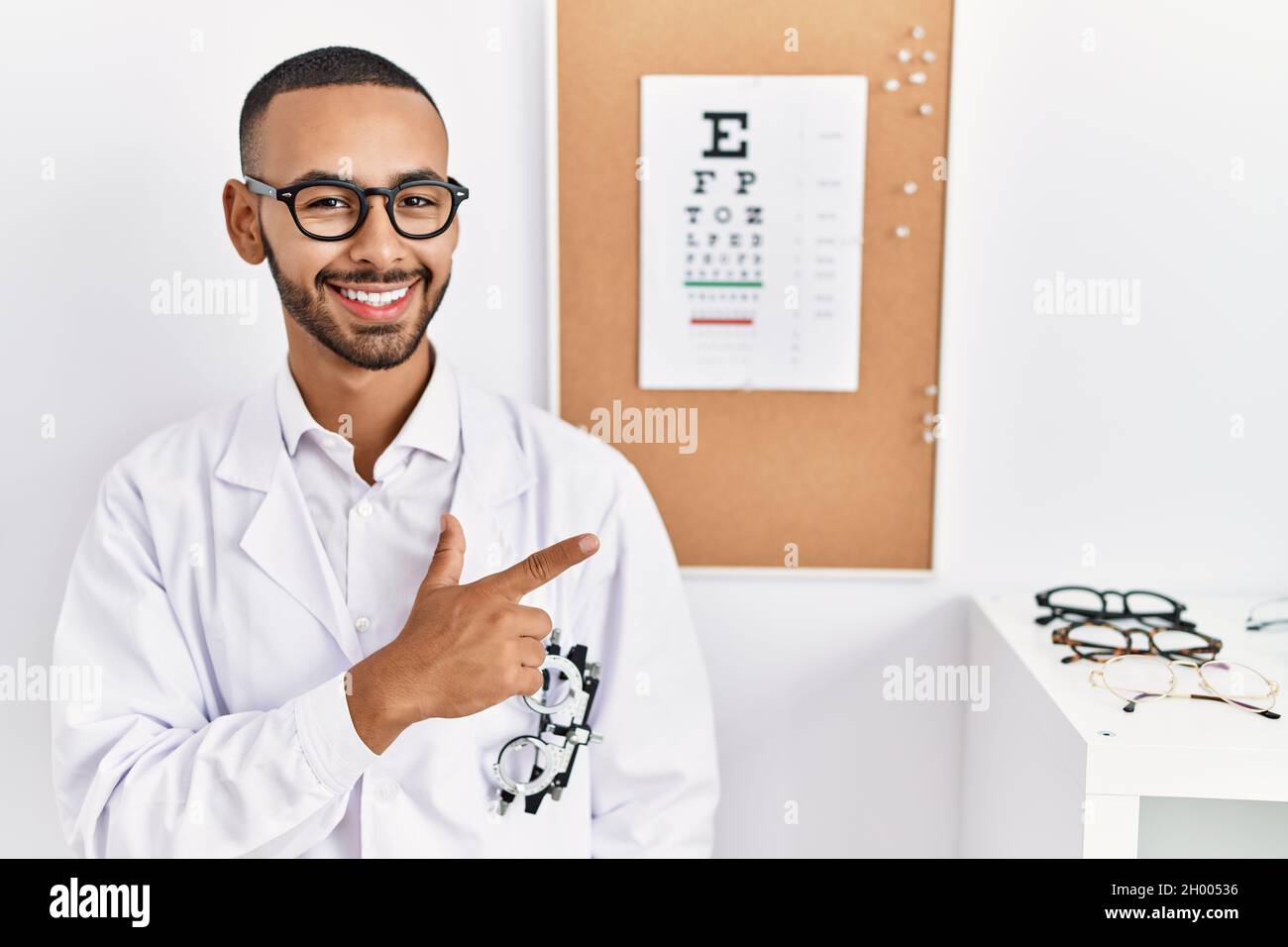 African american optician man standing by eyesight test cheerful with a ...