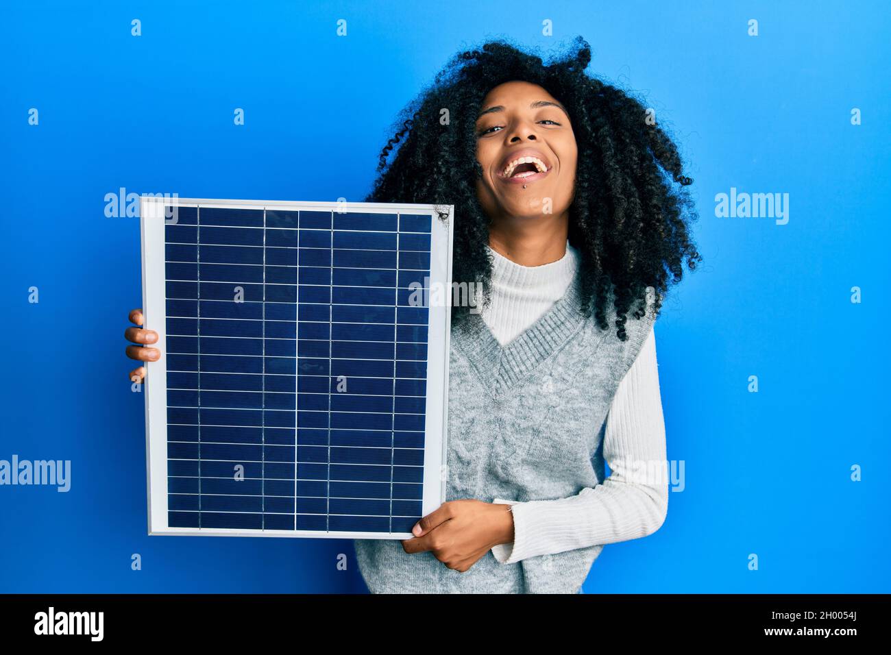 African american woman with afro hair holding photovoltaic solar panel ...