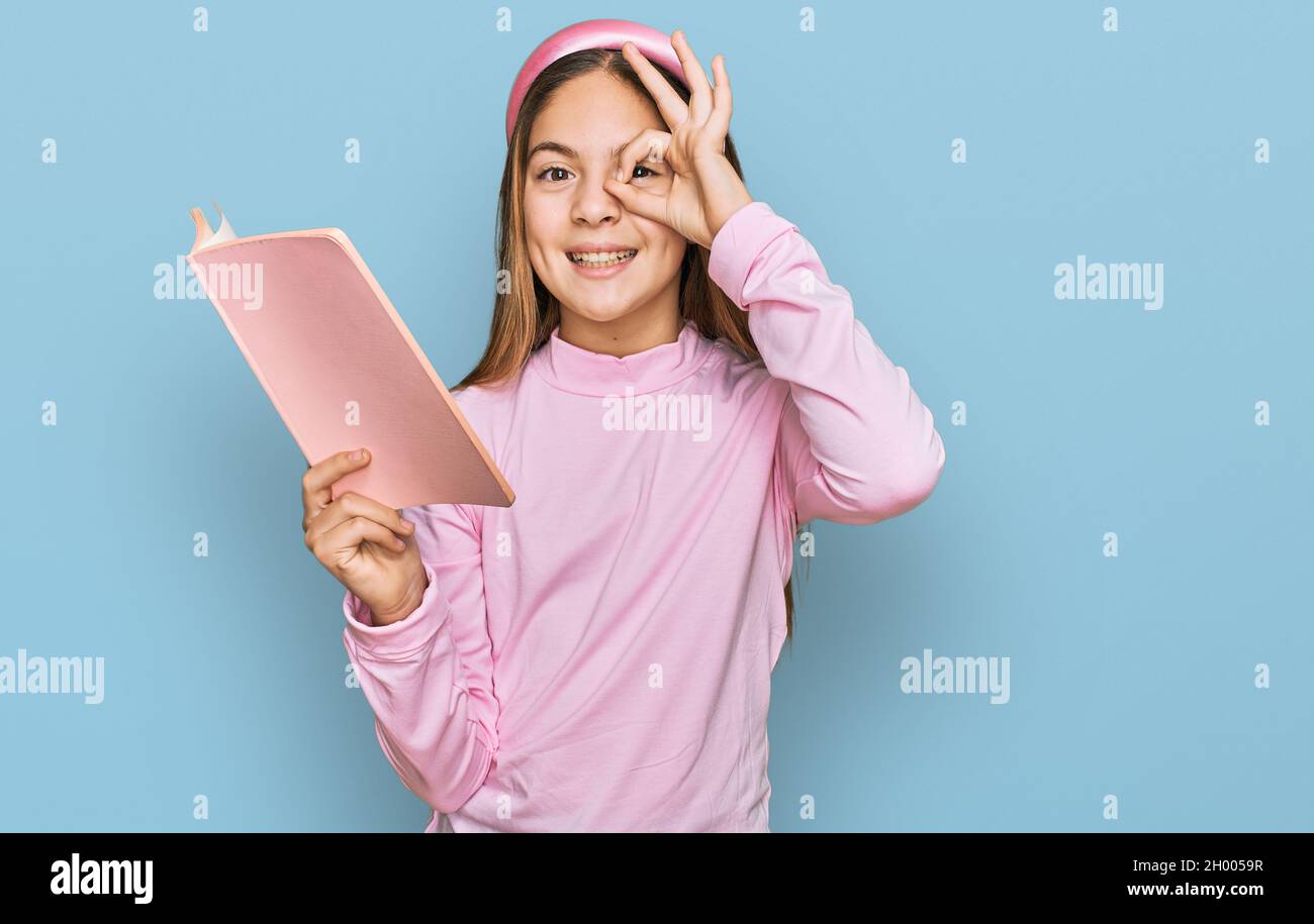 Beautiful brunette little girl reading a book smiling happy doing ok ...