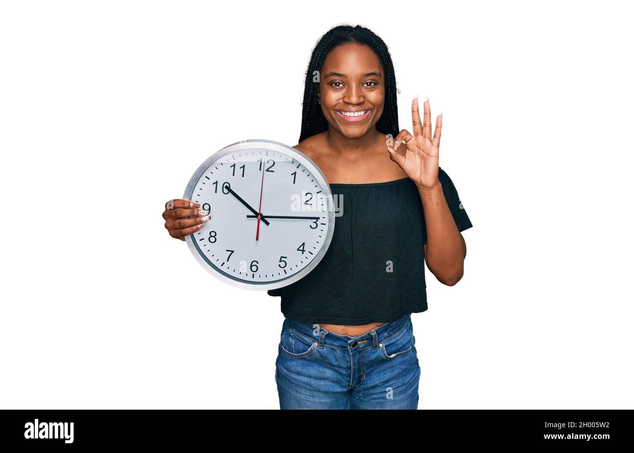 Young african american woman holding big clock doing ok sign with ...