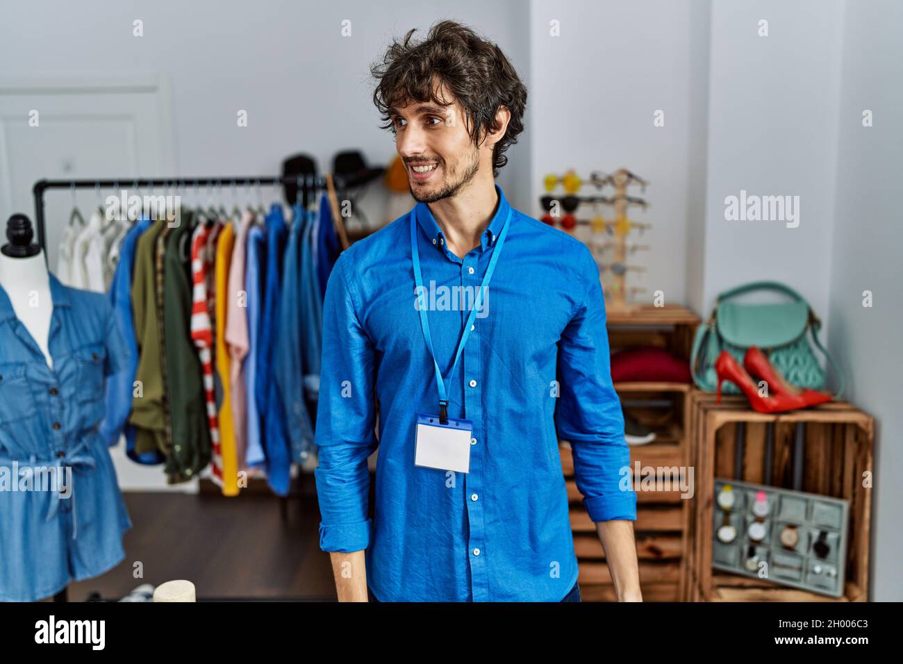 Young hispanic man working as manager at retail boutique looking away ...