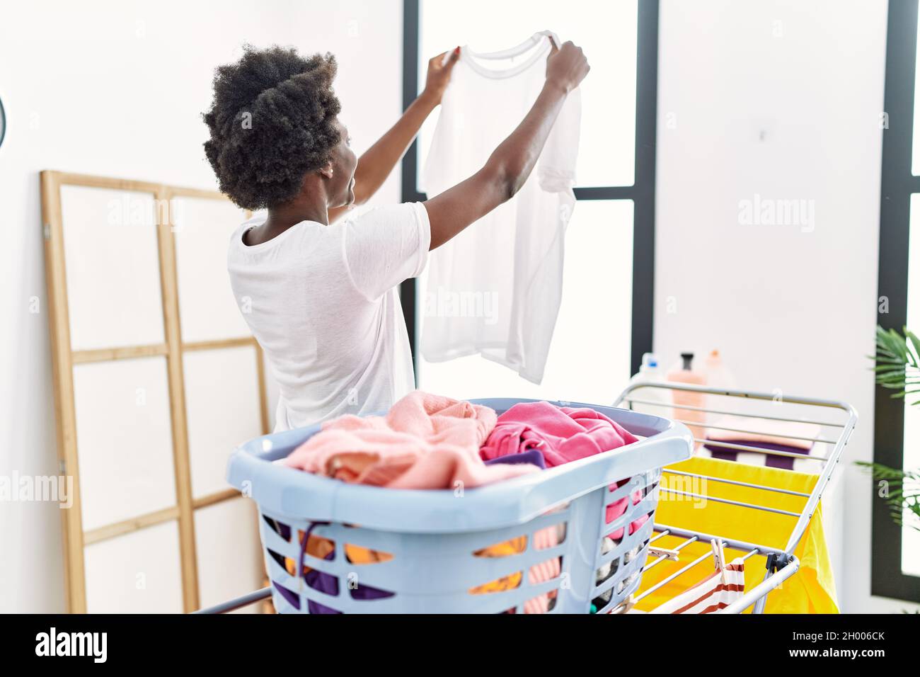 Young african american woman doing laundry looking clothes at laundry ...