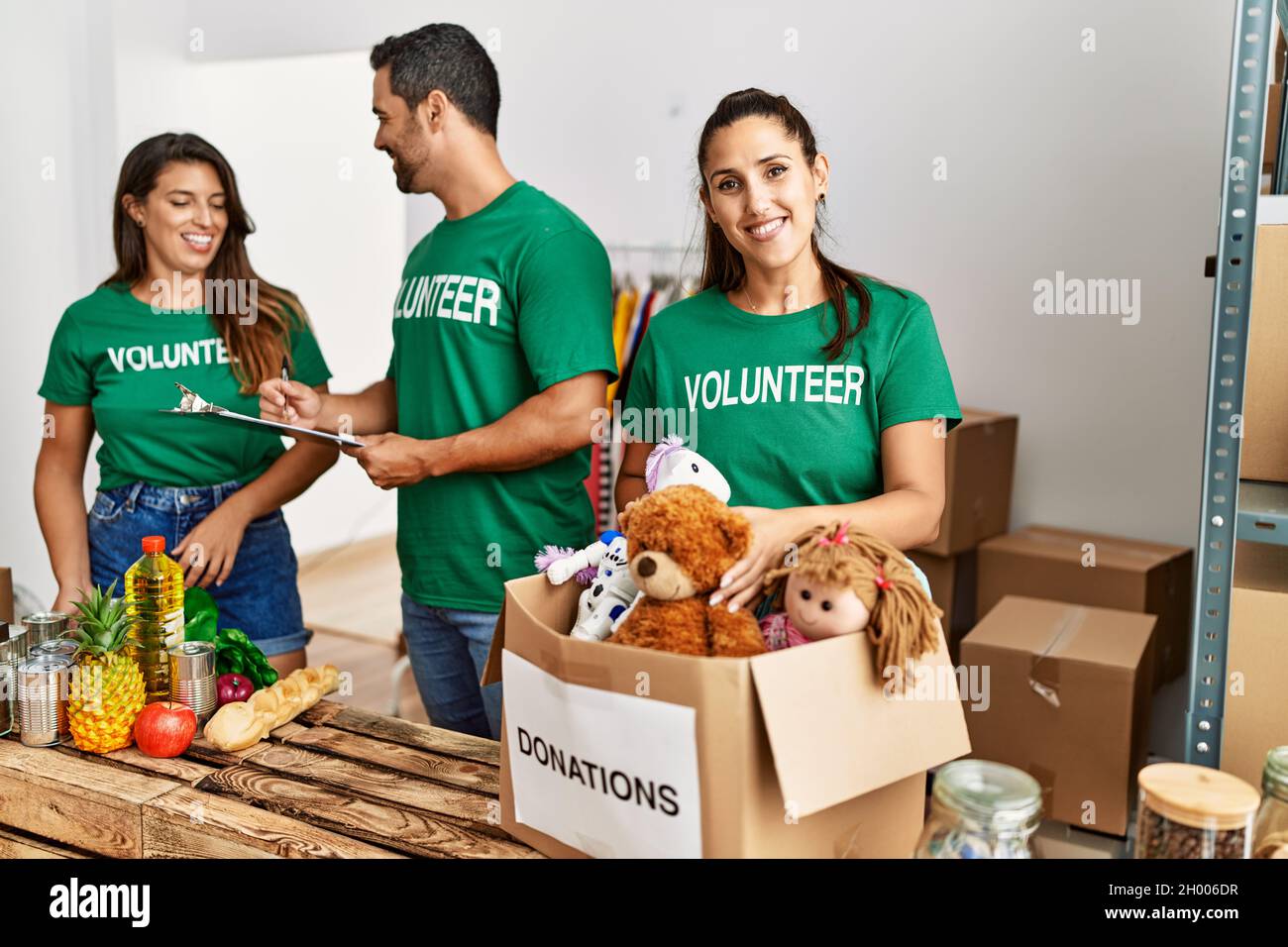 Group of hispanic volunteers smiling happy working at charity center ...