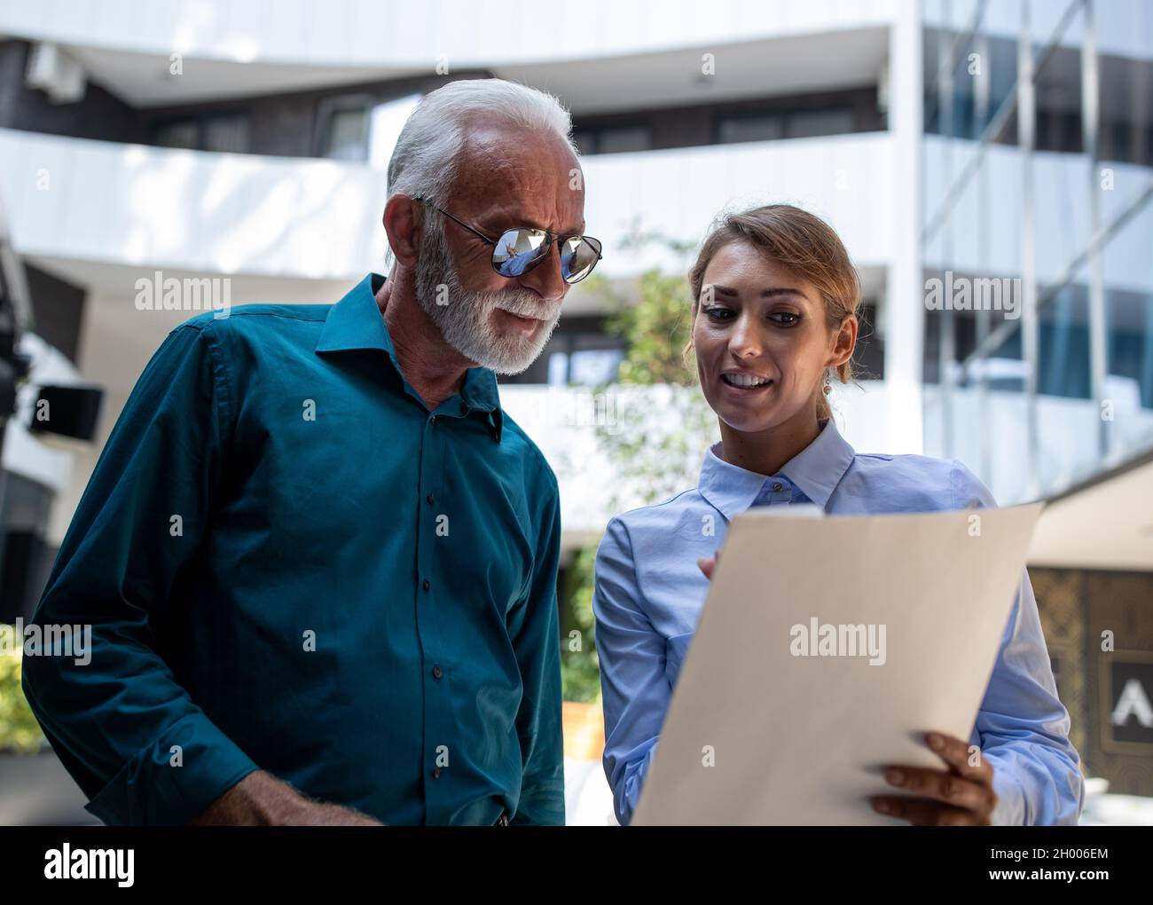 Mature businessman holding tablet and looking at young woman with ...