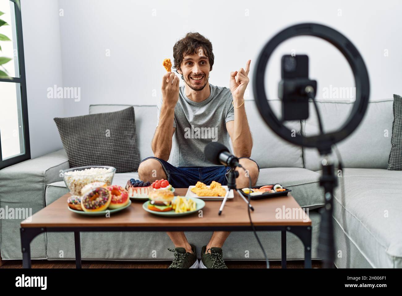Young hispanic man recording eating food video with smartphone at home ...