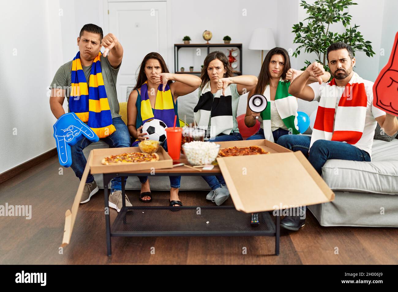 Group of young people wearing team scarf cheering football game with ...
