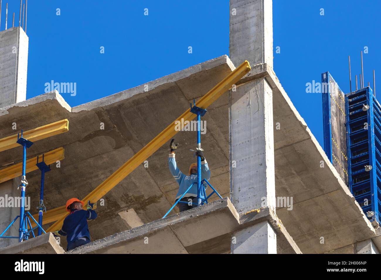 Construction site workers on high-rise building under construction ...