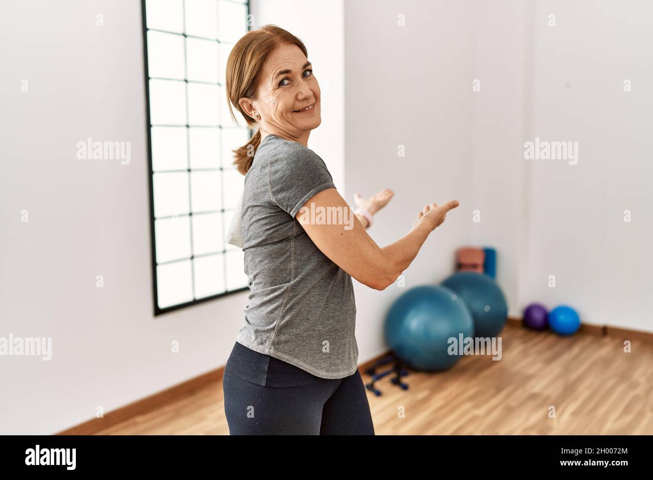 Middle age woman wearing sporty look training at the gym room inviting ...