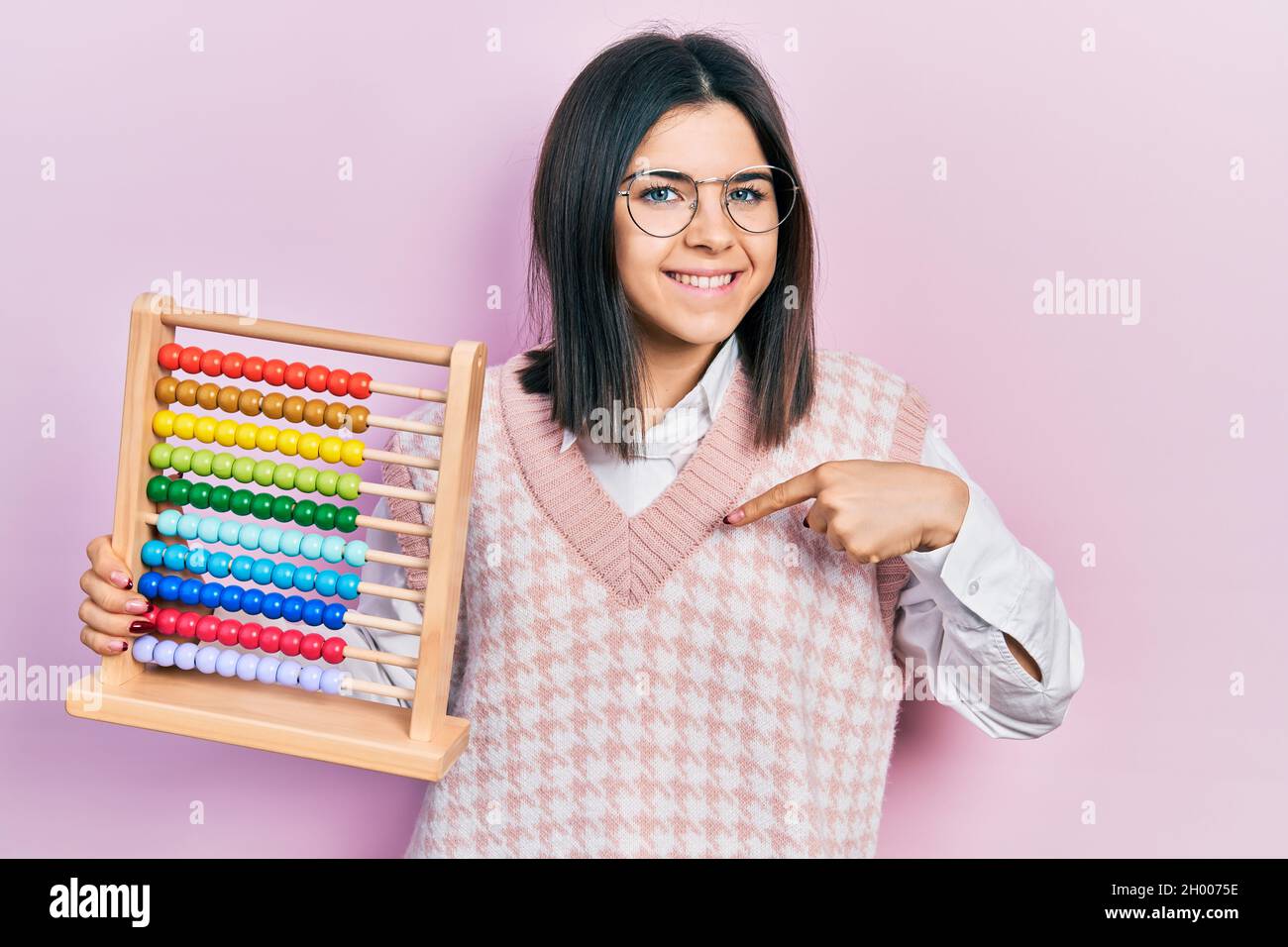 Young brunette woman holding traditional abacus pointing finger to one ...