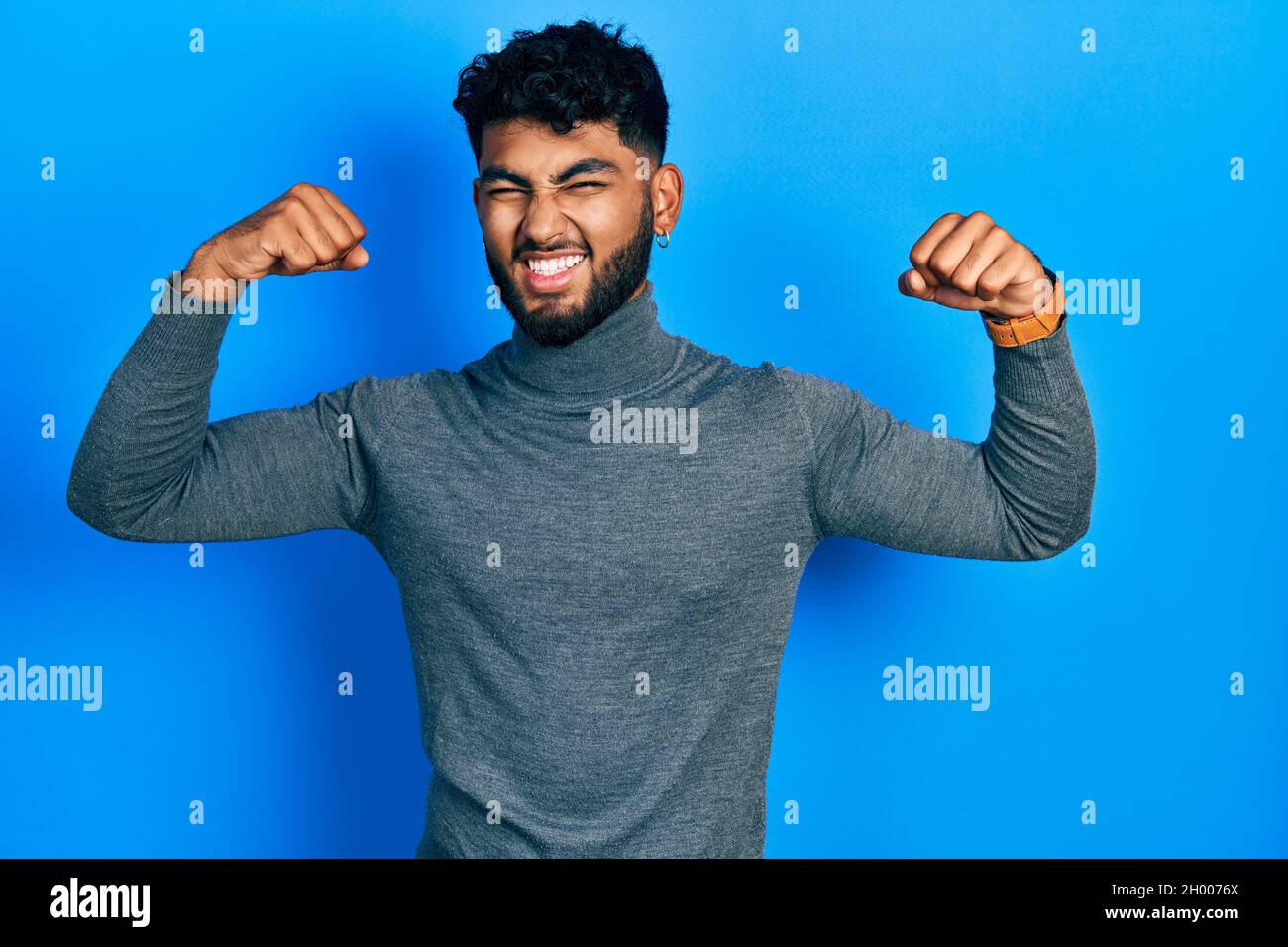 Arab man with beard wearing turtleneck sweater showing arms muscles ...