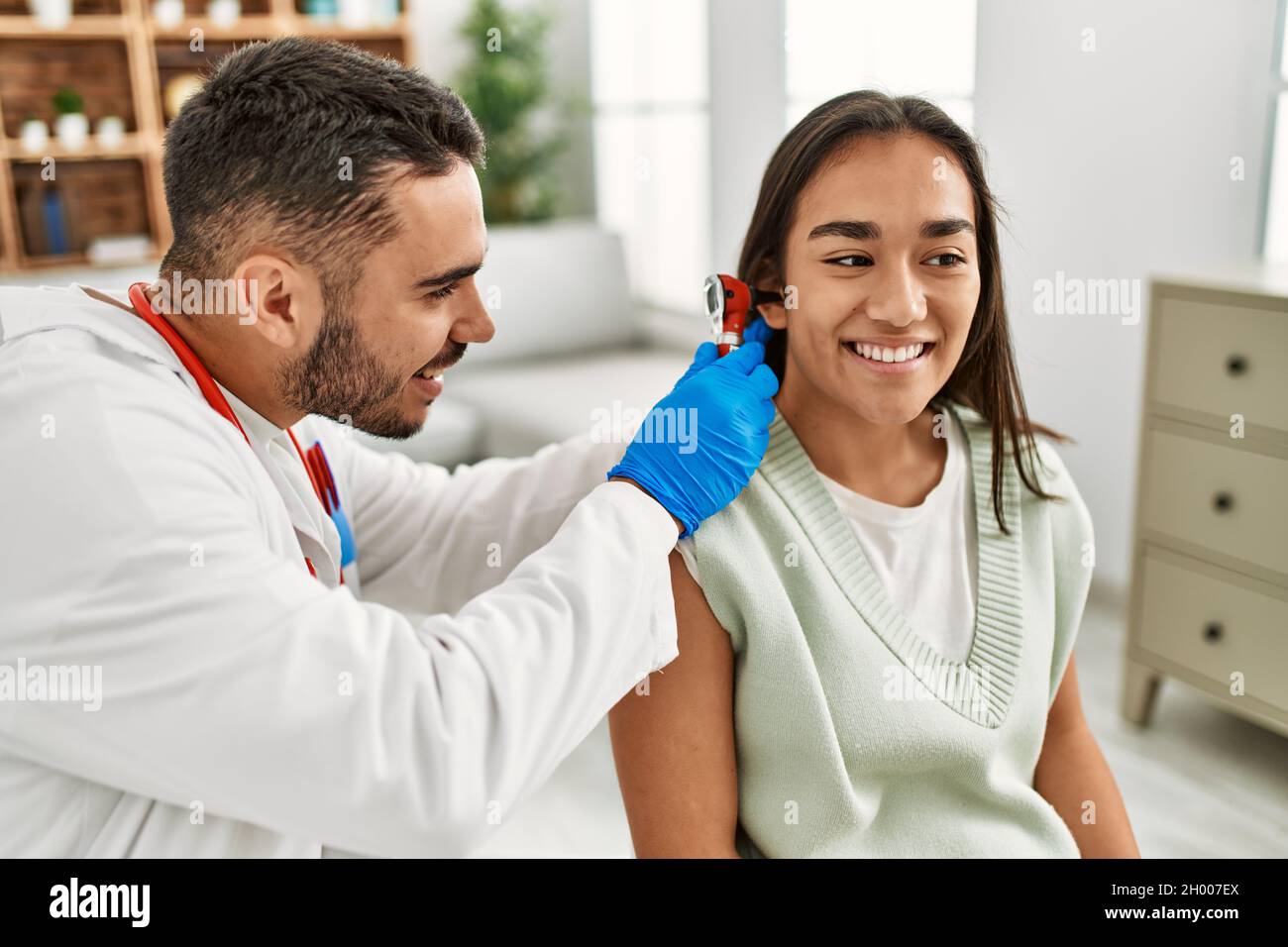 Doctor examining latin woman ear using otoscope at clinic Stock Photo ...