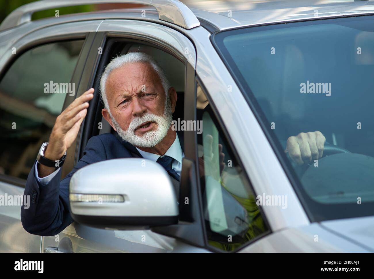 Frustraited man driving car and yelling throught window with raised arm ...