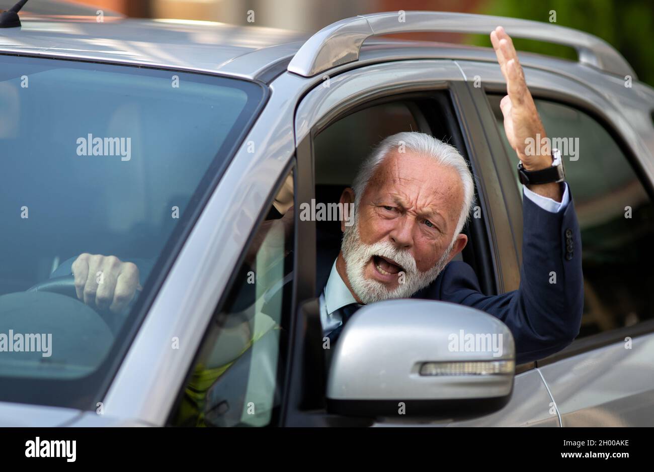 Frustraited man driving car and yelling throught window with raised arm ...
