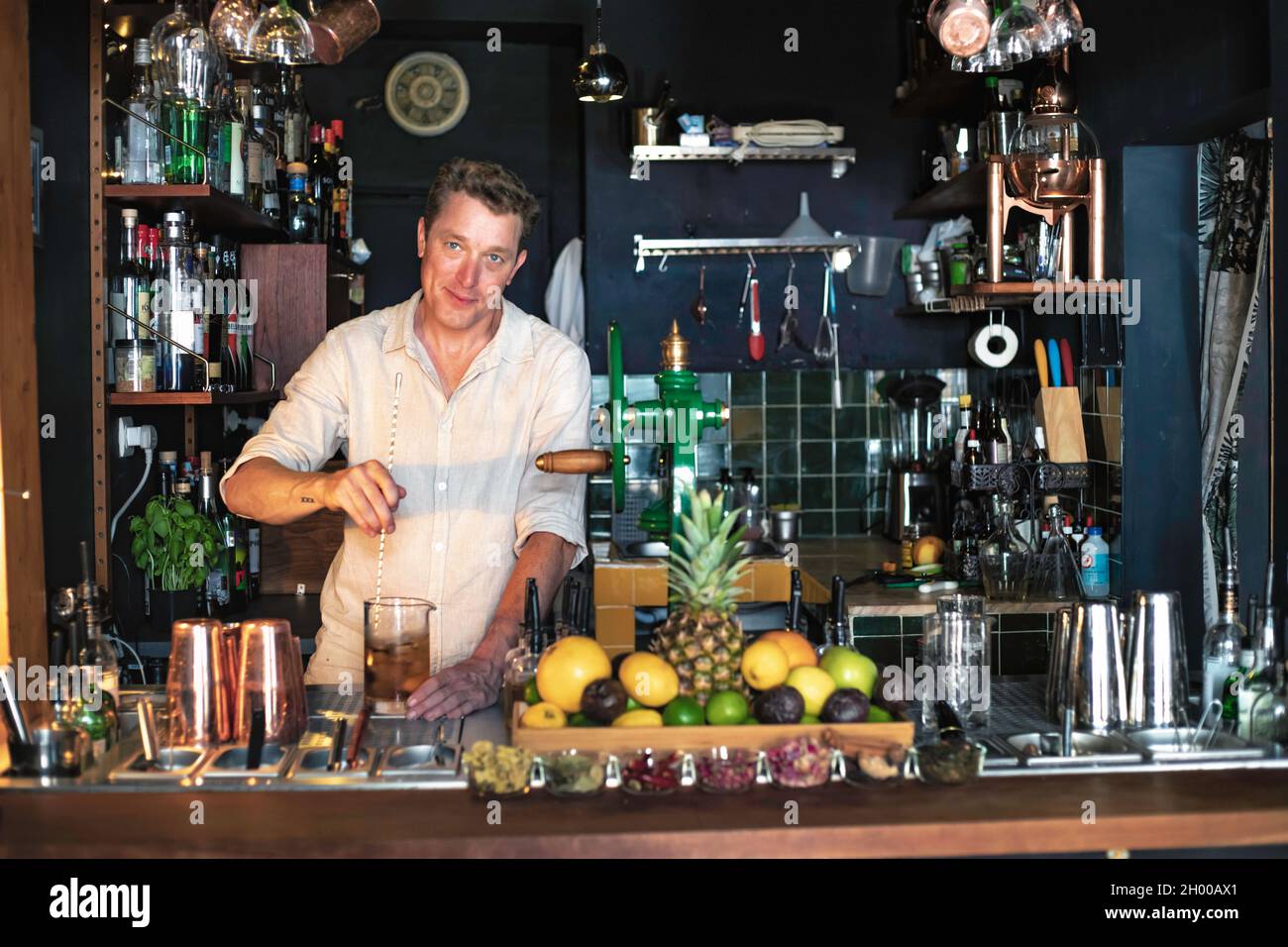 An expert bartender mixing a cocktail in a glass mixer with a long ...