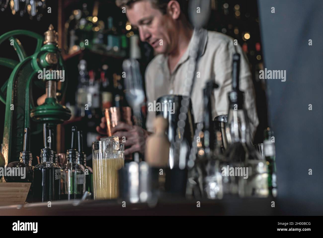 A professional bartender working in a fancy cocktail bar serving a ...