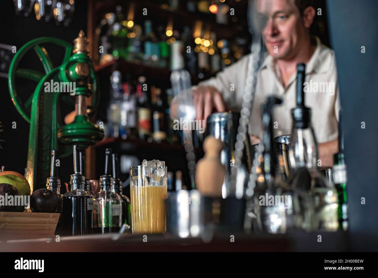 A professional bartender working in a fancy cocktail bar serving a ...