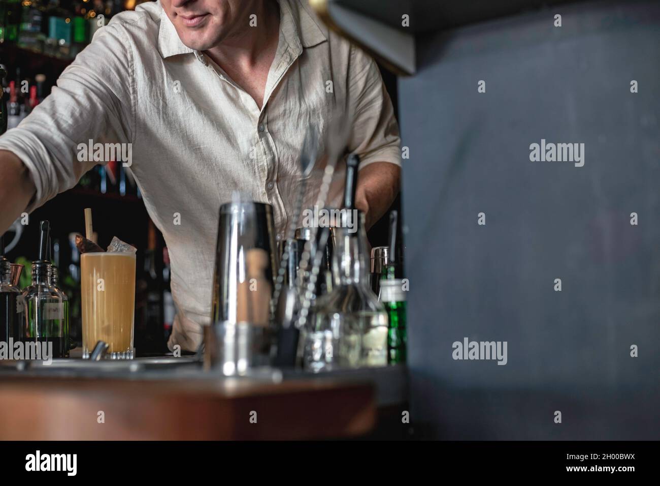 A professional bartender working in a fancy cocktail bar serving a ...