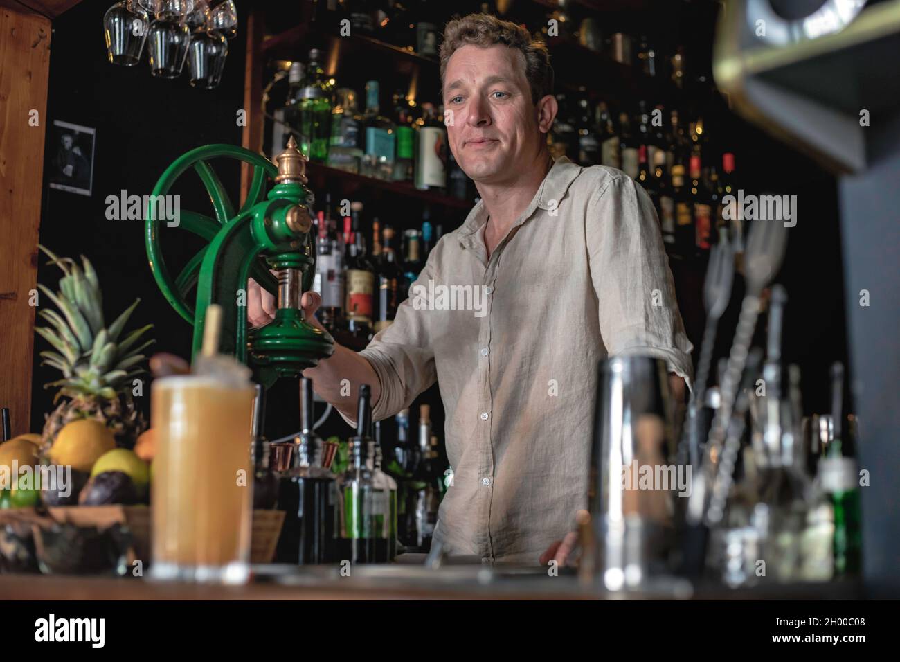 A professional bartender working in a fancy cocktail bar serving a ...