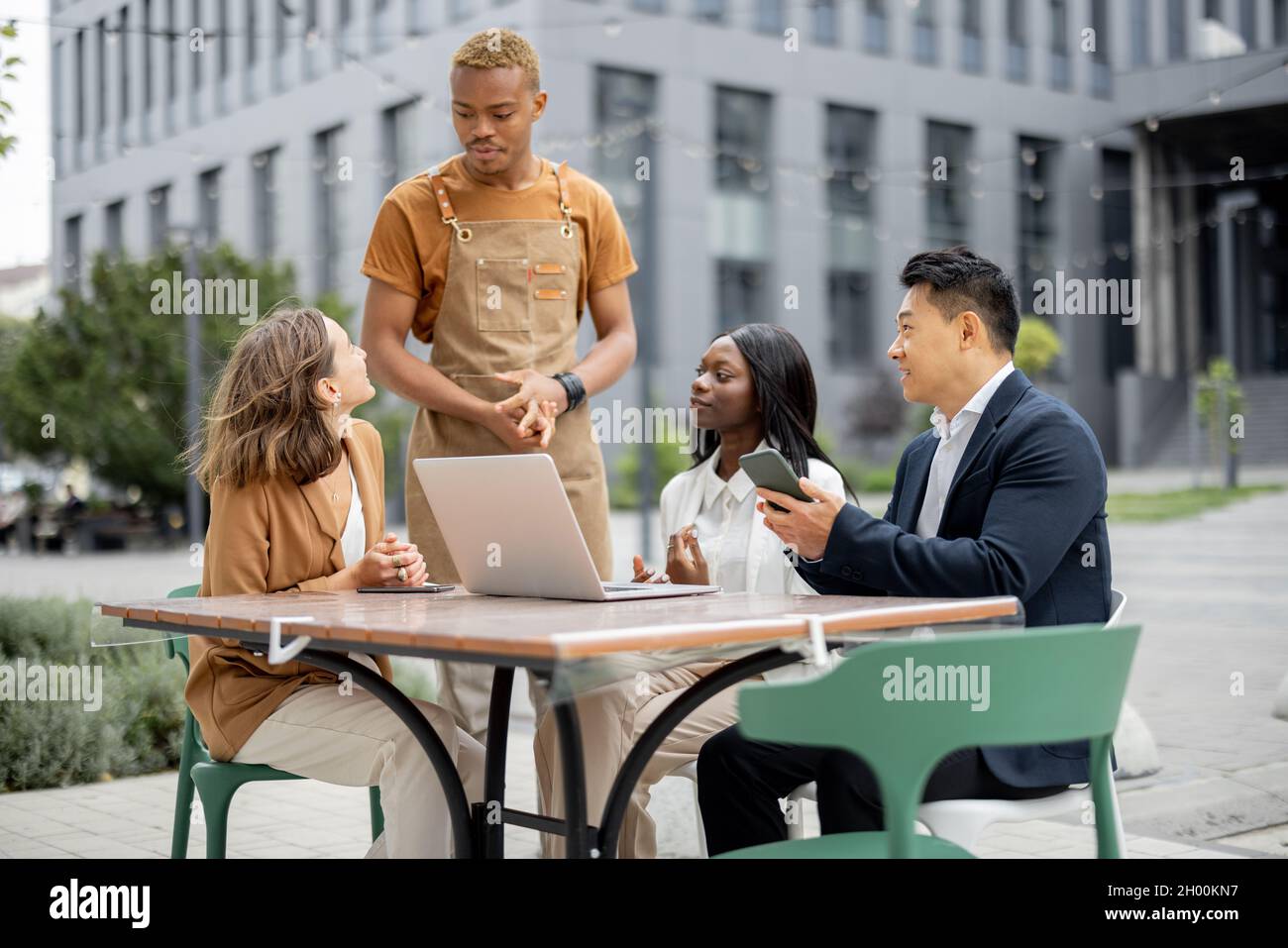 Waiter taking order from clients at outdoor cafe Stock Photo - Alamy