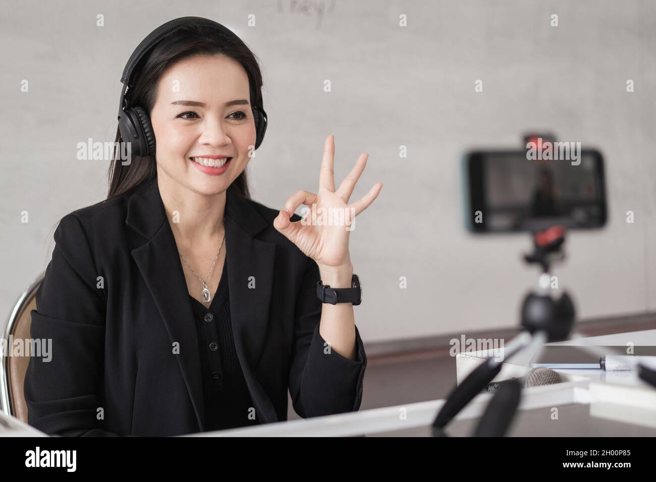 A Southeast Asian female tutor gesturing the ok sign while giving an ...